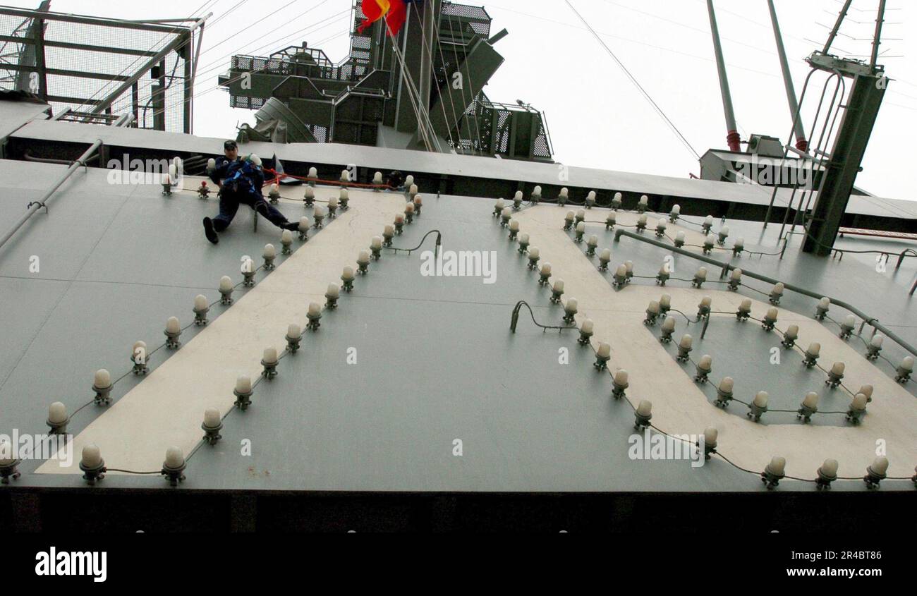 US Navy Electrician's Mate 3rd Class change light bulbs on the island ...