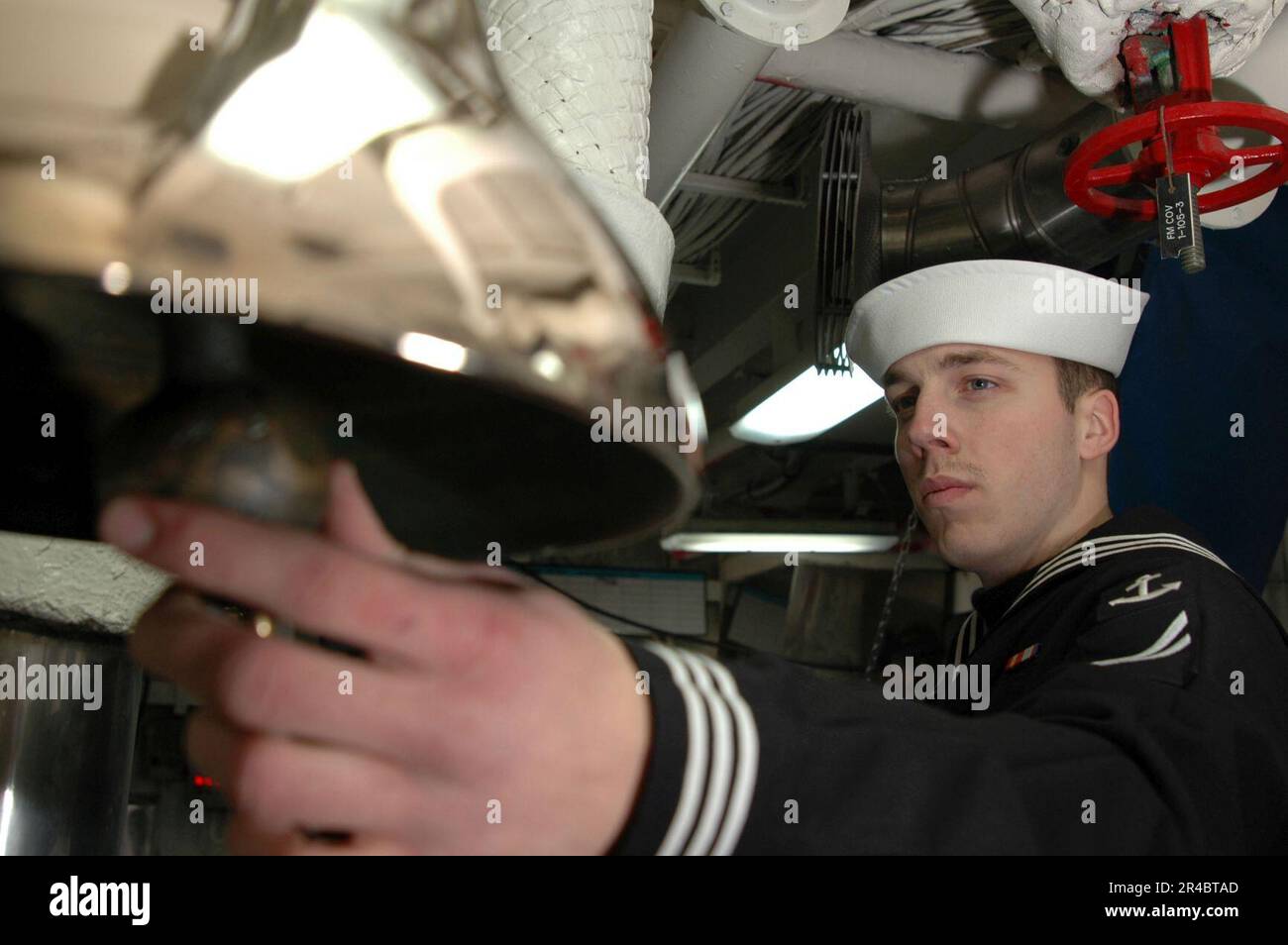 US Navy Seaman Apprentice rings the ship's bell on the quarterdeck ...