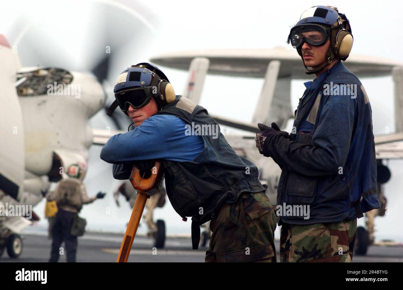US Navy Flight deck personnel wait to chock and chain an aircraft on ...