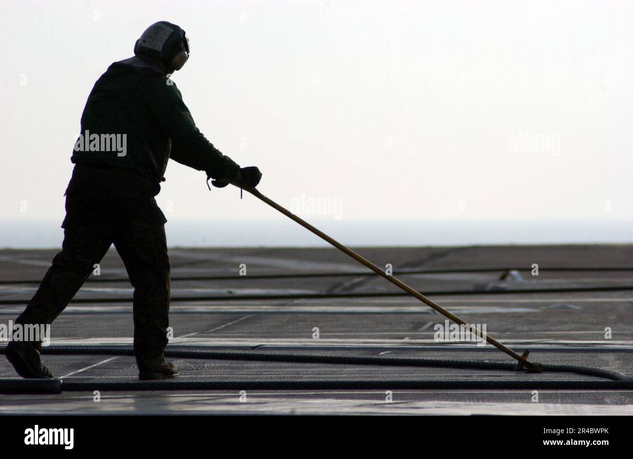 US Navy An arresting gear crew member guides an arresting wire back ...