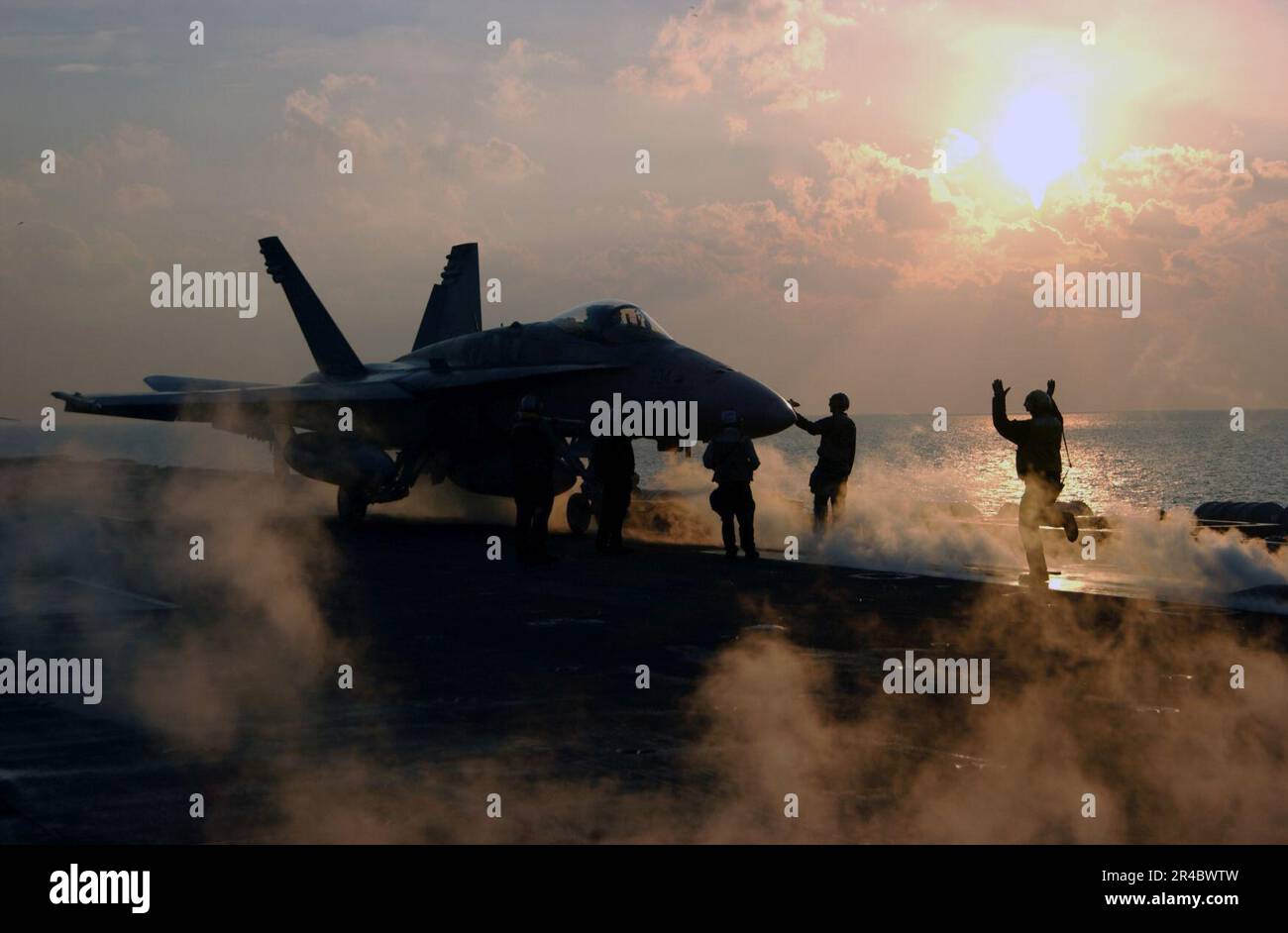 US Navy A flight deck handler guides an F-A-18C Hornet into position ...