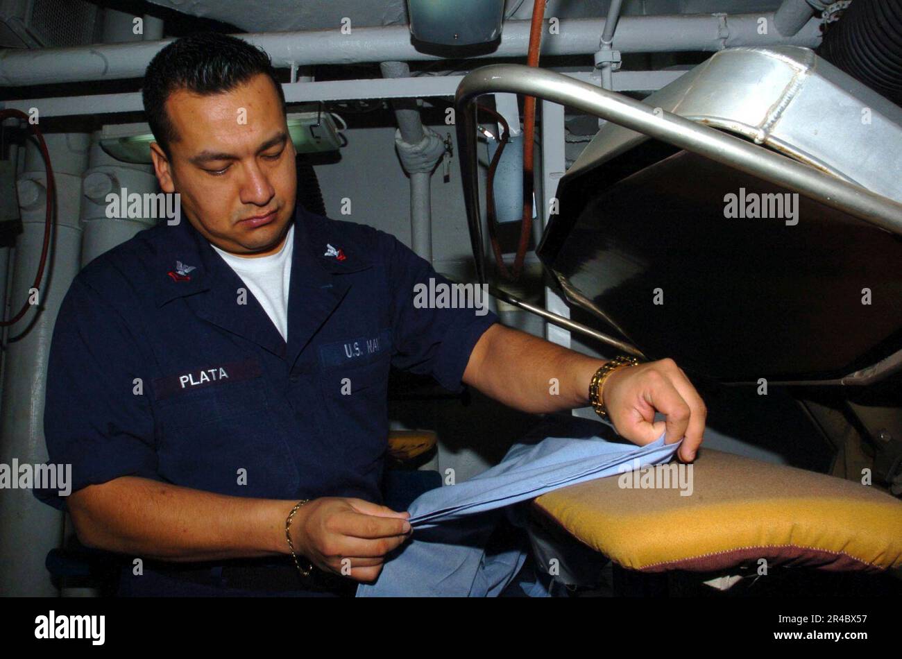 US Navy Ship's Serviceman 2nd Class presses a utility uniform in the ...
