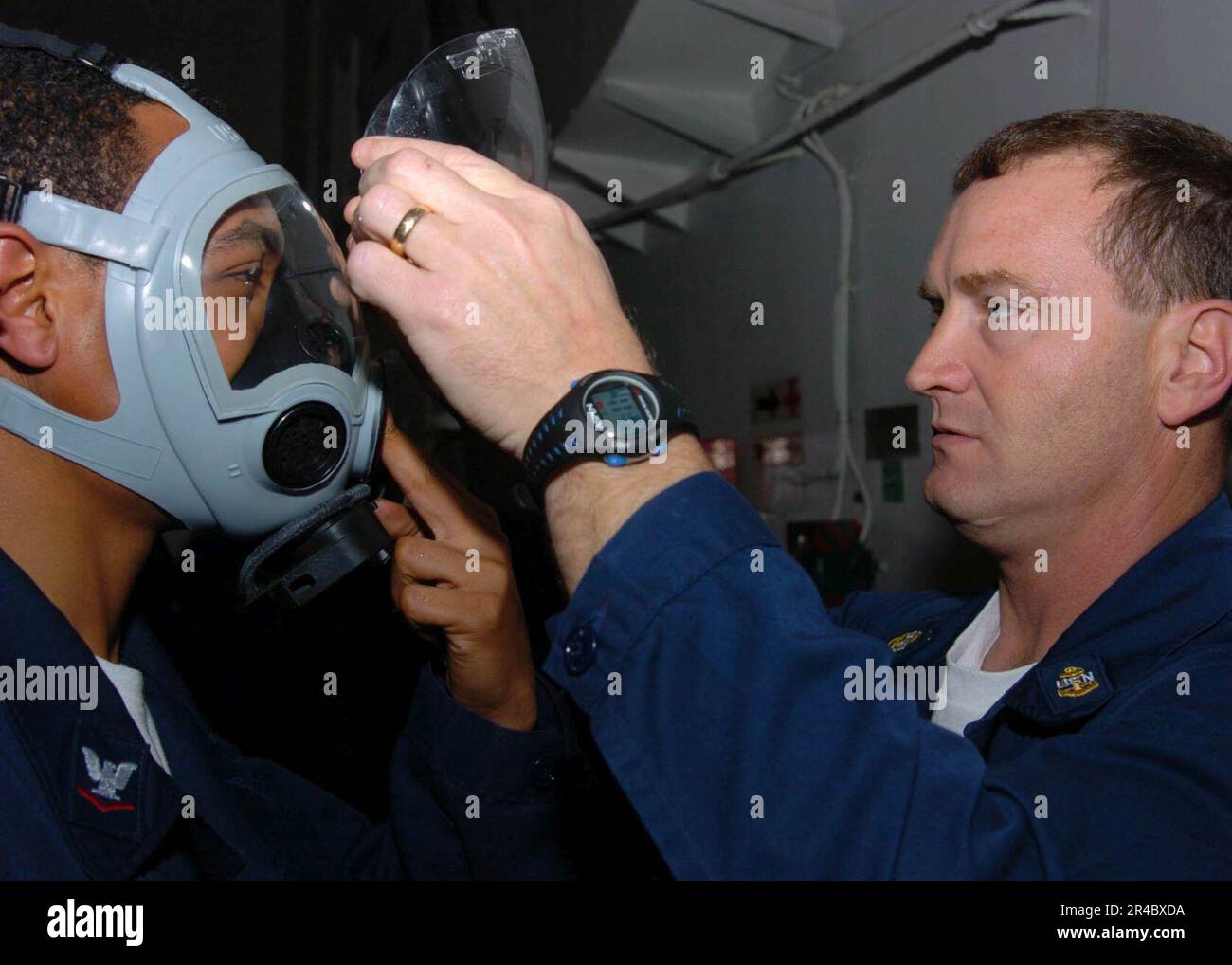 US Navy Chief Damage Controlman, removes the face shield from a Sailor ...