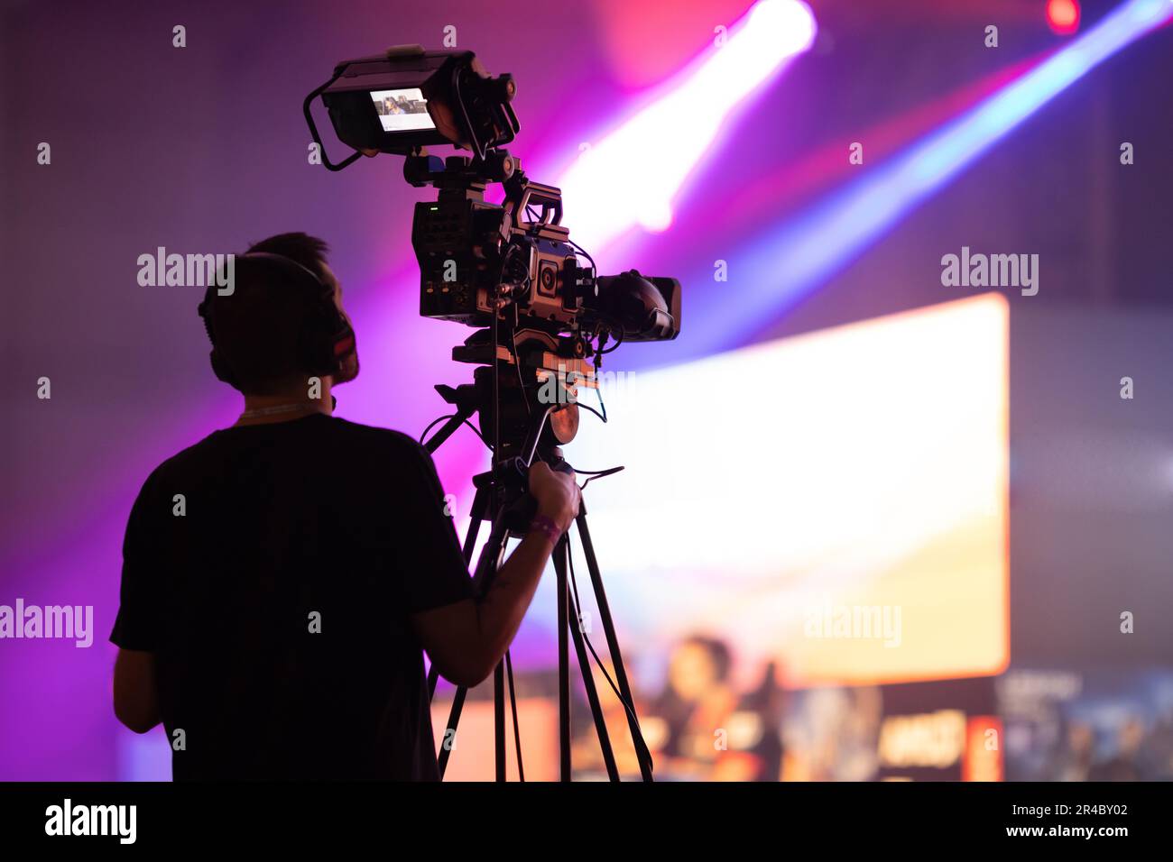 A man working with TV camera and shooting the scene at the gaming expo ...