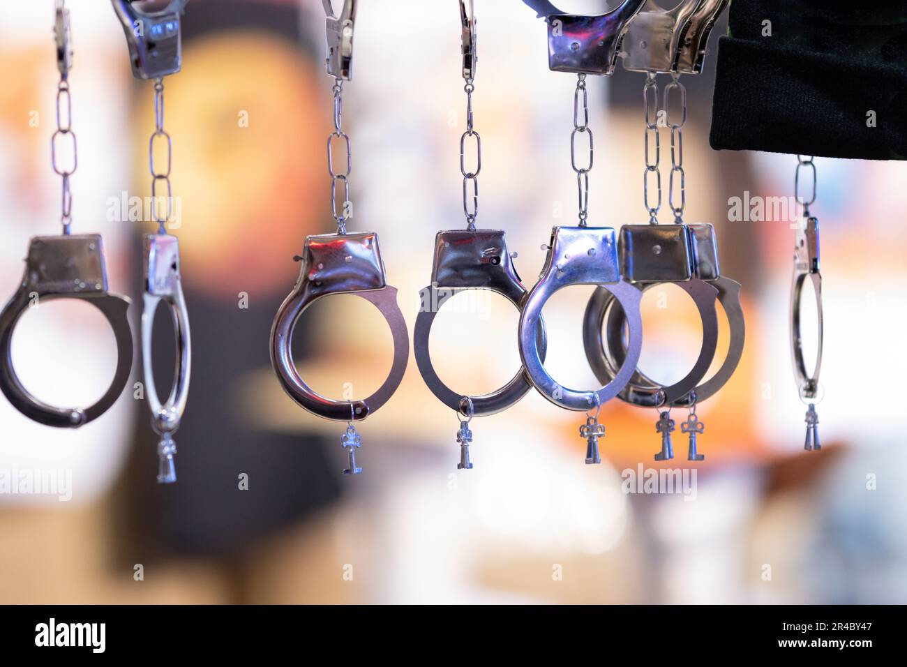 Several suspended steel handcuffs with a little keys on a blurry ...