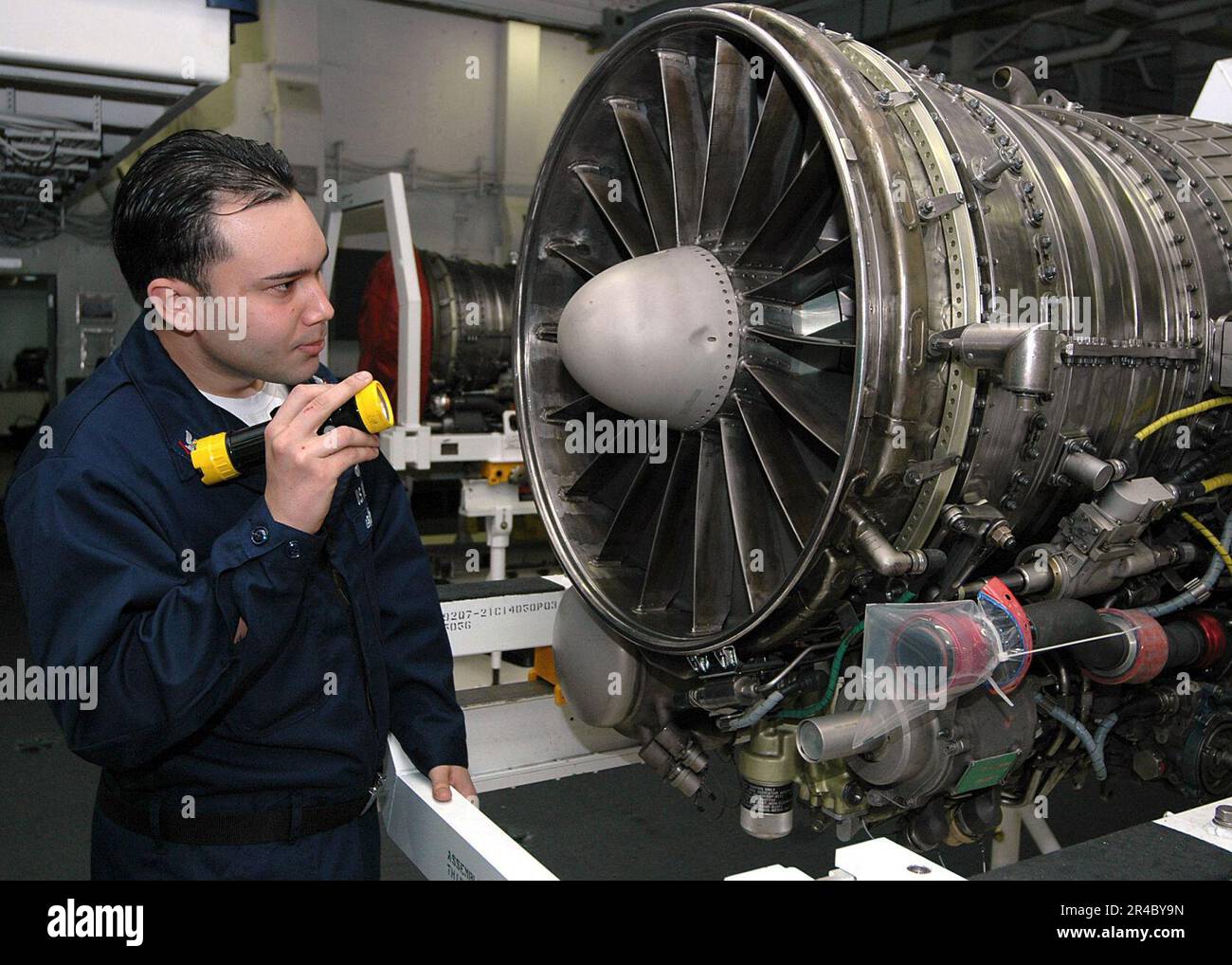 US Navy Aviation Machinist's Mate 3rd Class checks a jet engine for ...