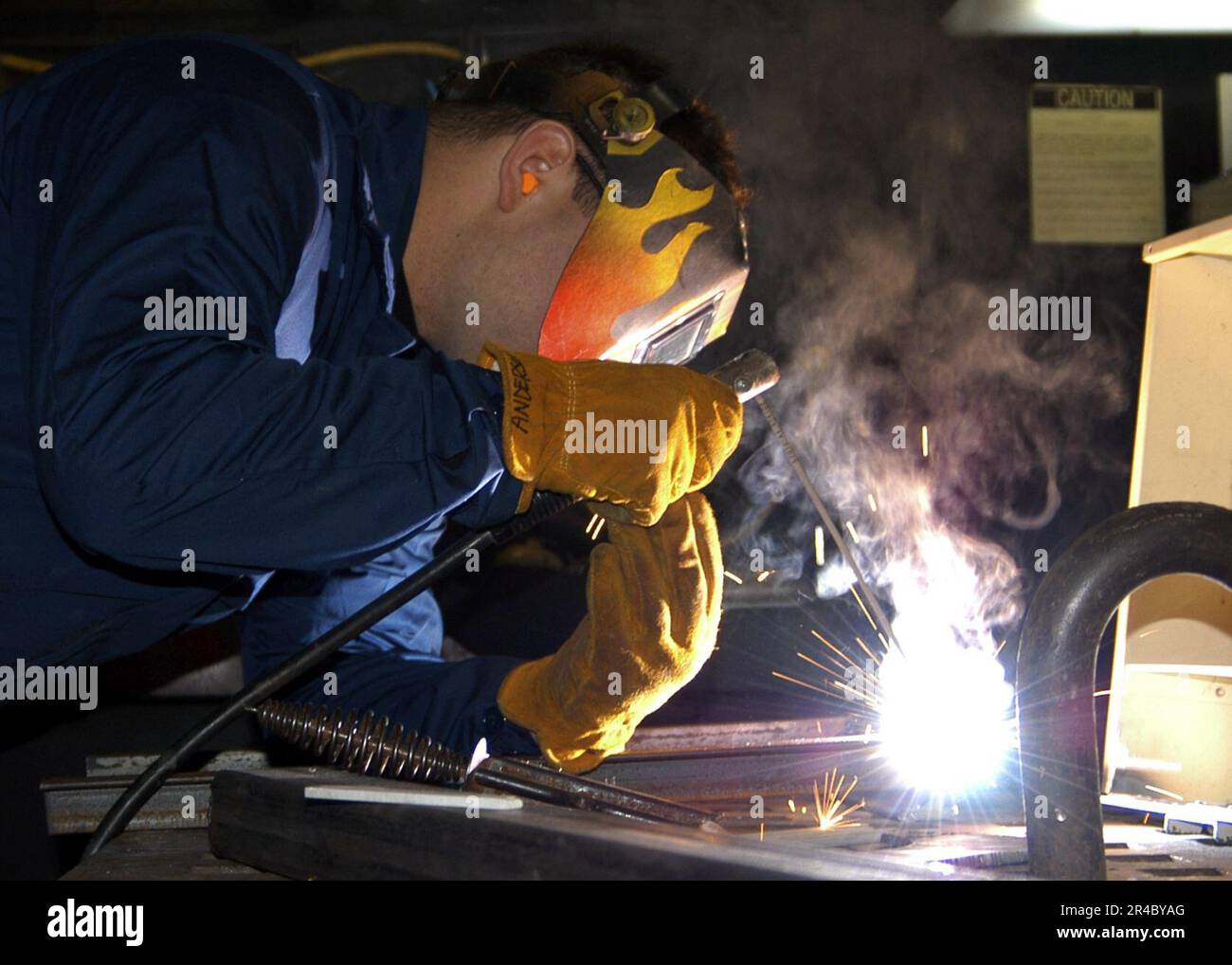 US Navy Hull Technician 2nd Class welds a bracket together to hold ...