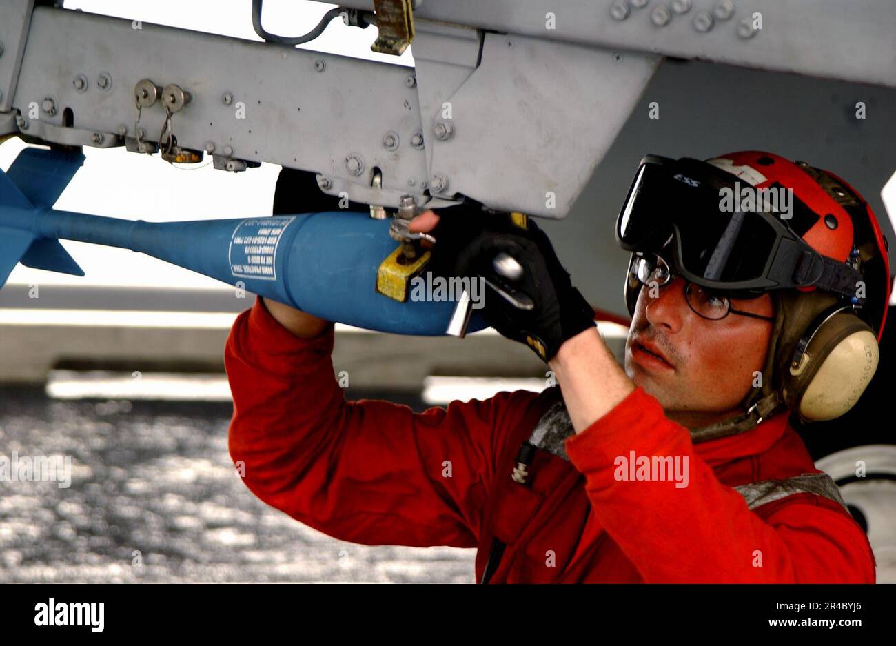 US Navy An aviation ordnanceman attaches a MK-76 practice bombs onto an ...