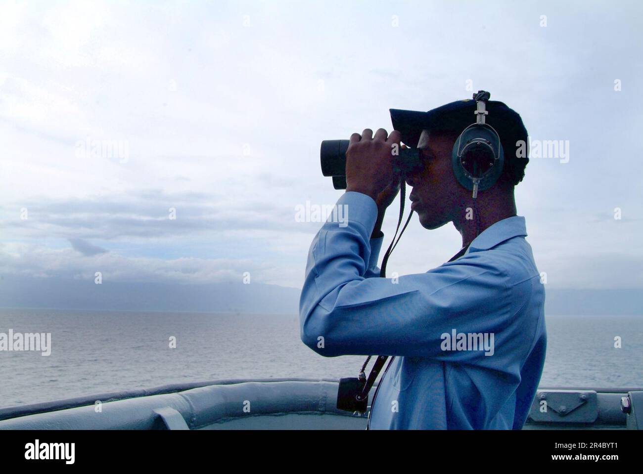 US Navy Seaman stands watch on the bridge wing as the landing ship USS ...