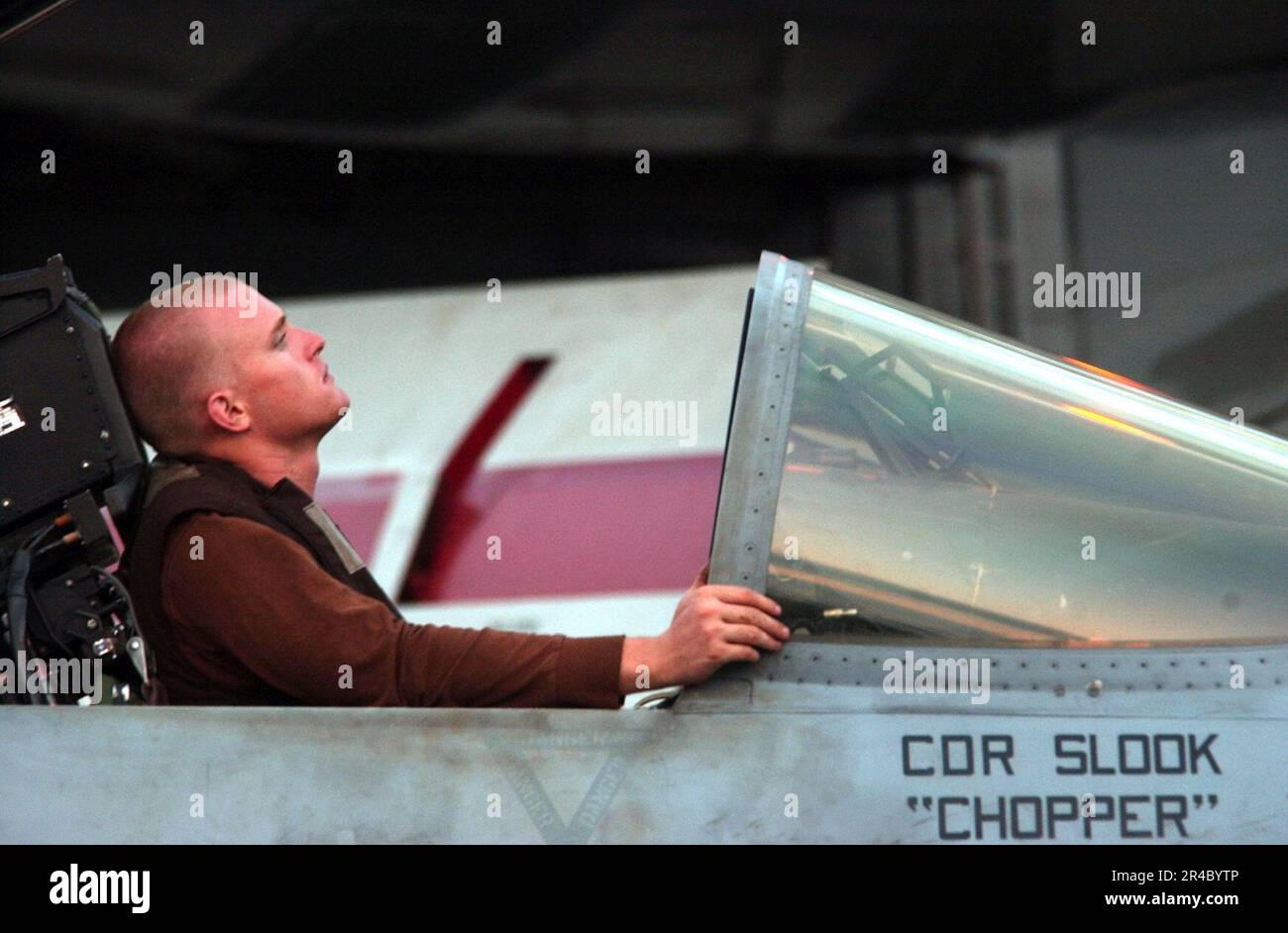 US Navy A plane captain watches the sunset from the cockpit of an F-A ...