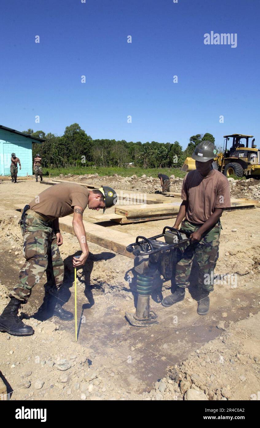 US Navy U.S. Navy Seabee Builder Construction measures the trench depth ...
