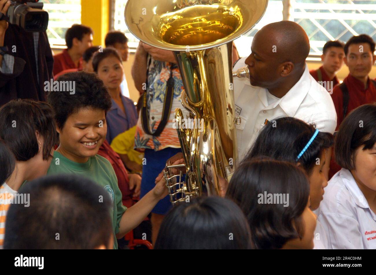 US Navy Musician 2nd Class helps a child operate a tuba during a ...