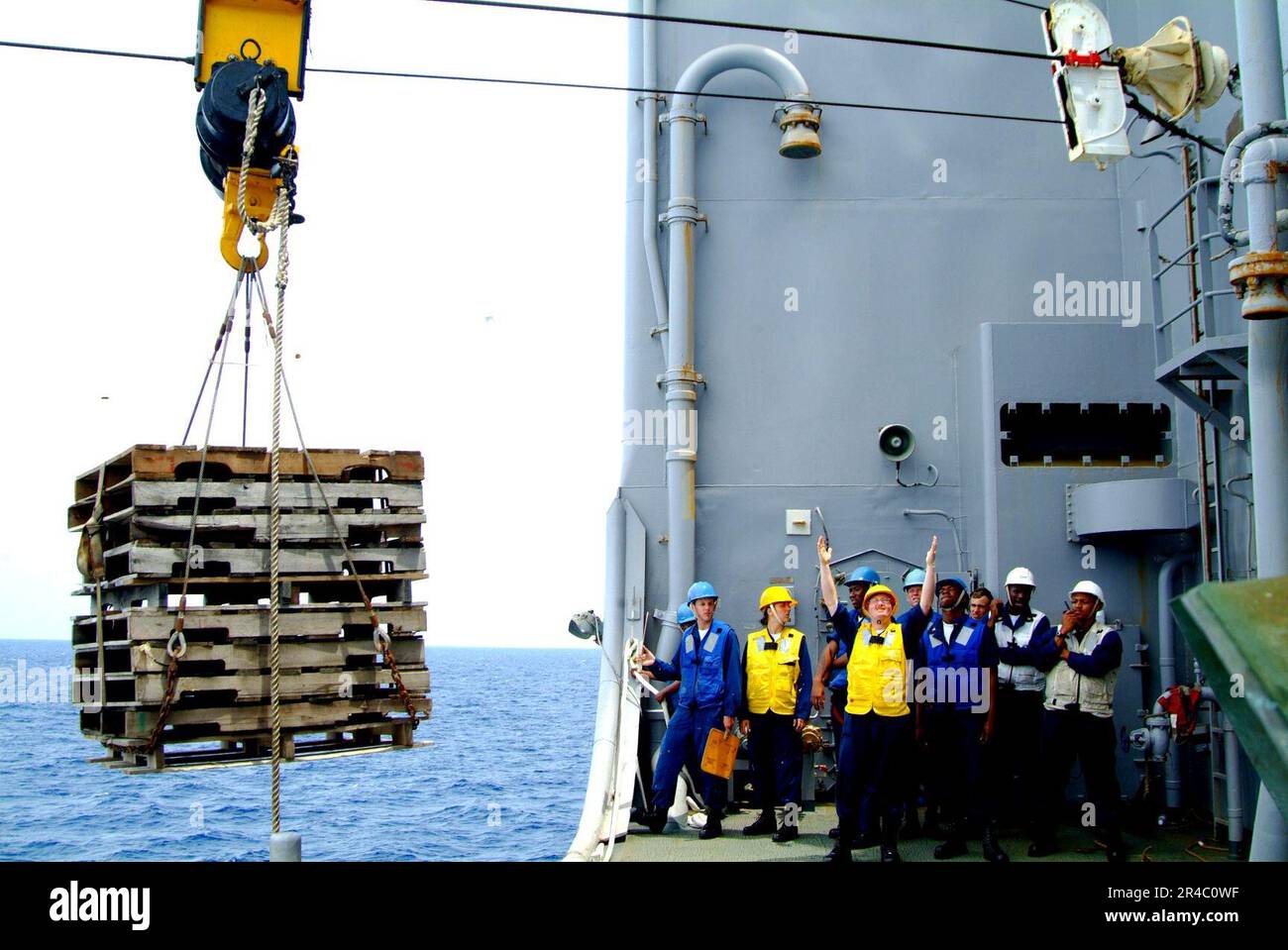 US Navy Sailors gives hand signals to move pallets from the Military ...