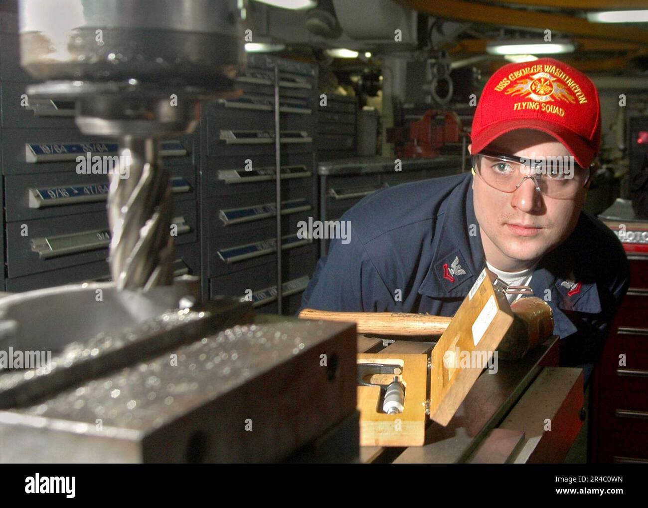 US Navy Machinery Repairman 2nd Class monitors a milling machine in the ...