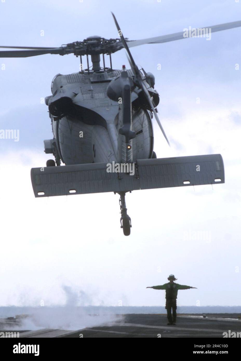 US Navy A landing signalman enlisted directs a landing of a SH-60 ...