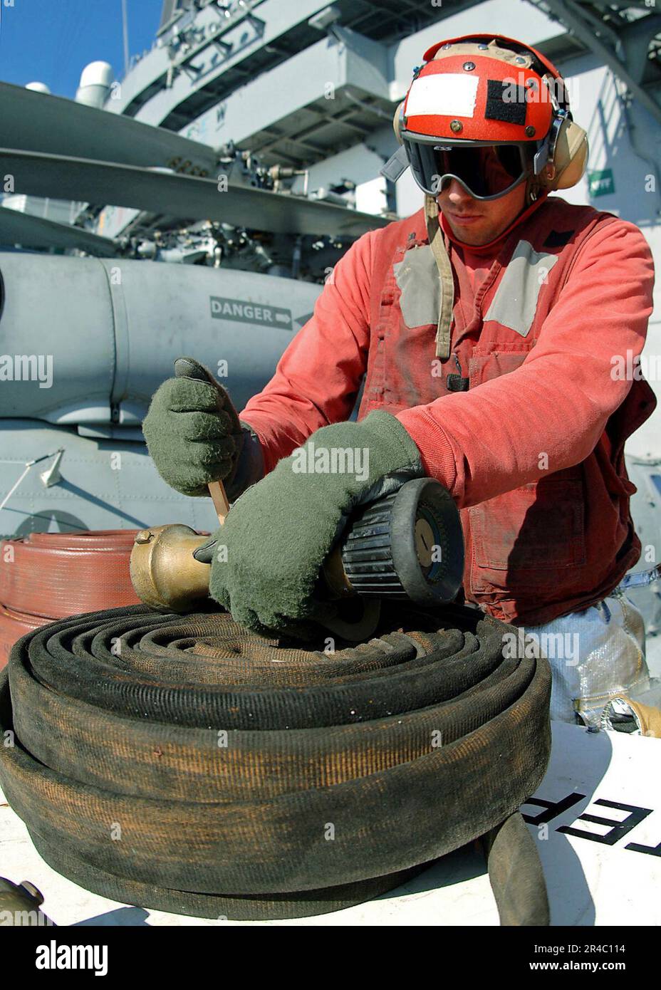 US Navy Aviation Boatswain's Mate repairs a fire hose for the Crash and ...