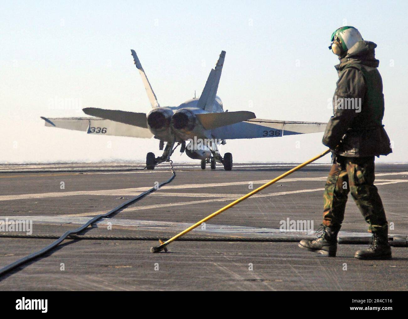US Navy Airman guides a retracting arresting gear wire after an F-A-18C ...