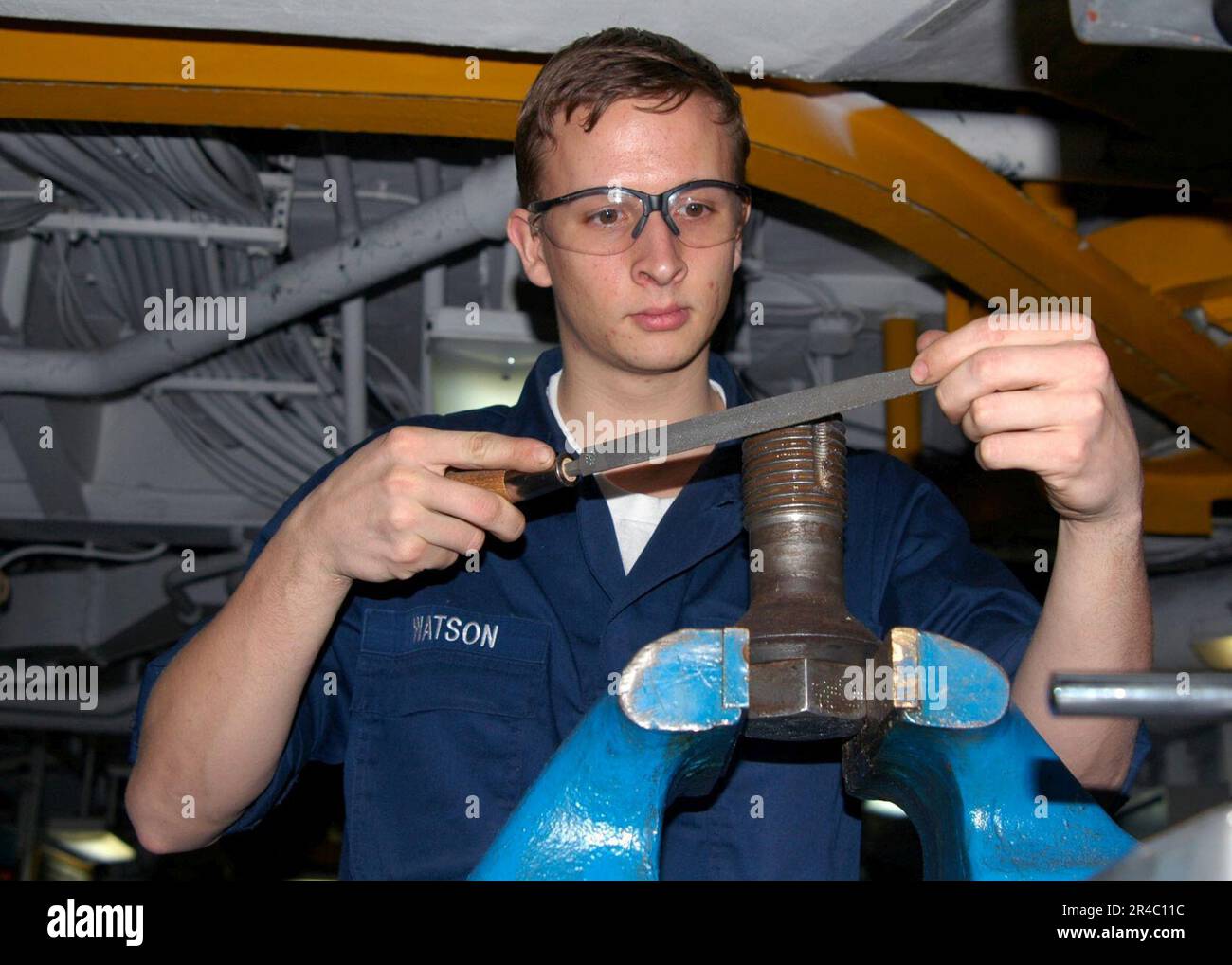 US Navy Machinery Repairman 3rd Class files down a bolt from a water ...