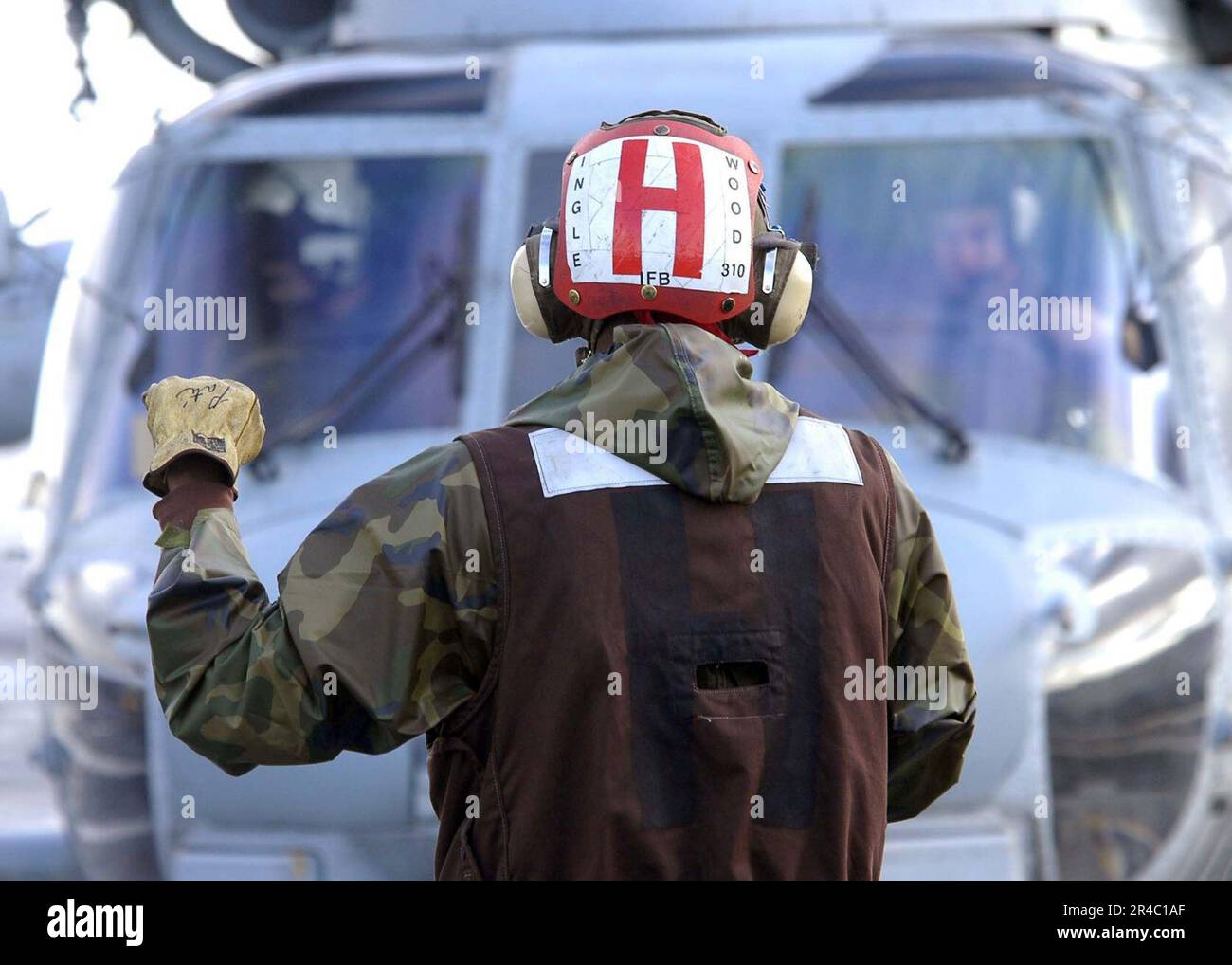 US Navy A landing signal enlisted gestures to the pilots of a SH-60B ...