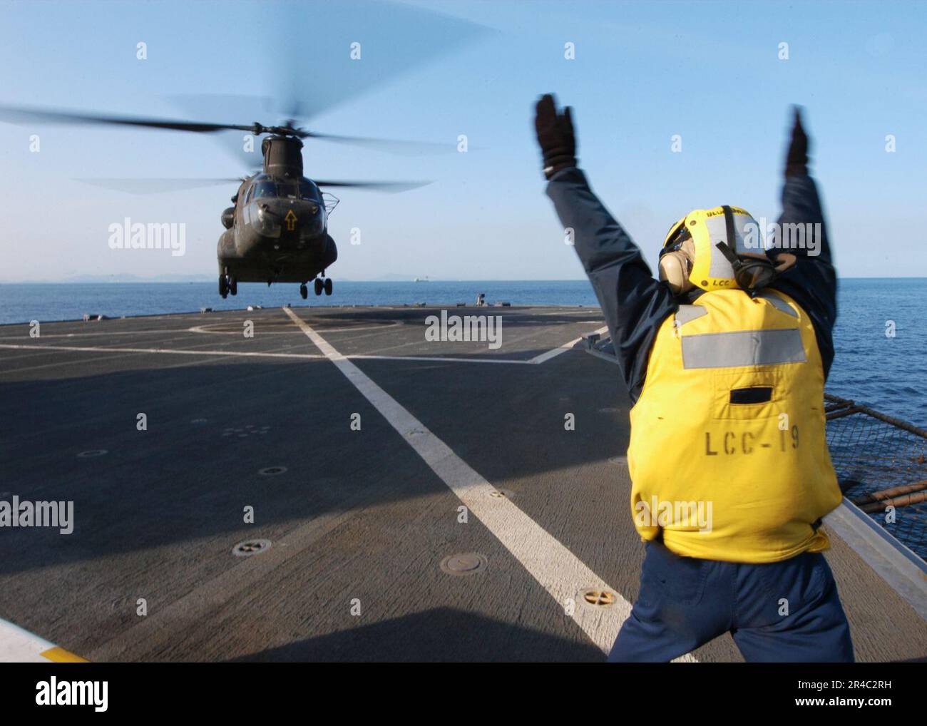 US Navy Boatswain's Mate 2nd Class signals to an Army CH-47 Chinook ...