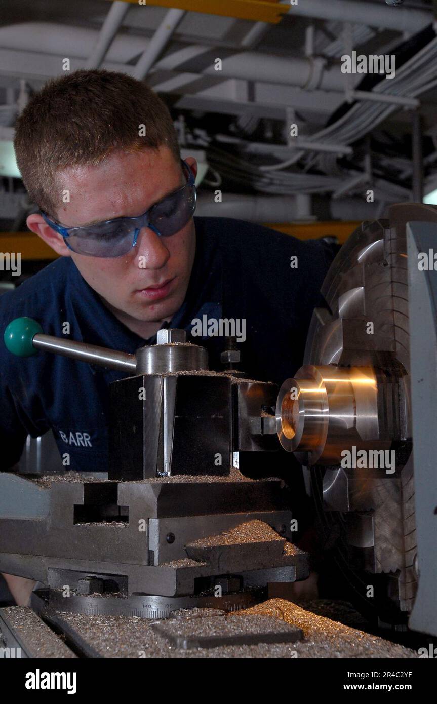 US Navy Machinery Repairman Fireman uses a lathe to machine a bronze ...