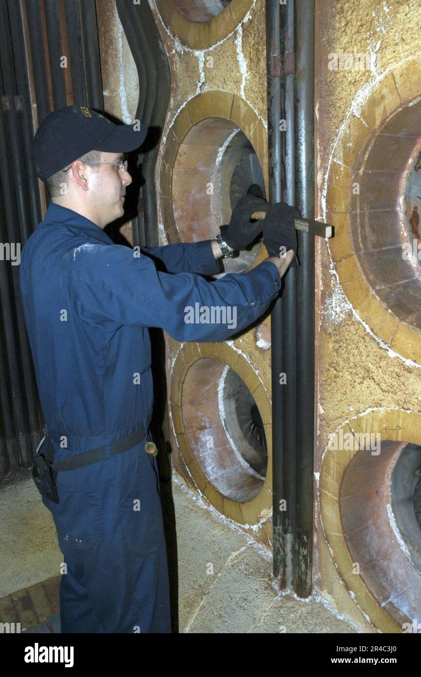 US Navy Machinist Mate 3rd Class wire brushes excess chemical build-up ...