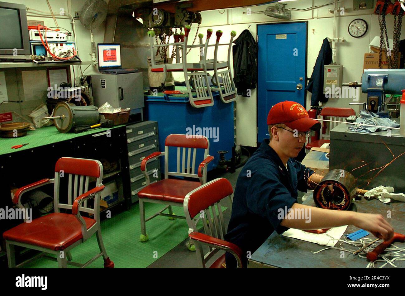 US Navy Electrician's Mate 3rd Class repairs a motor in the rewind shop ...