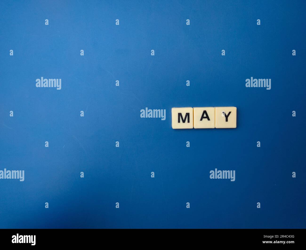 A blue and white sign with the word "May" written in a Scrabble-style ...