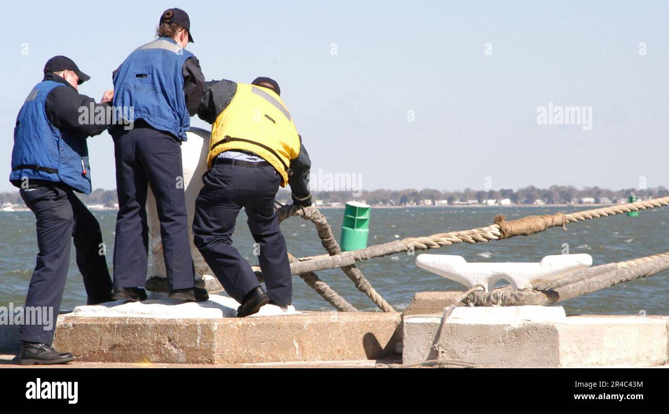US Navy Line-handlers work to remove mooring lines on the pier while ...