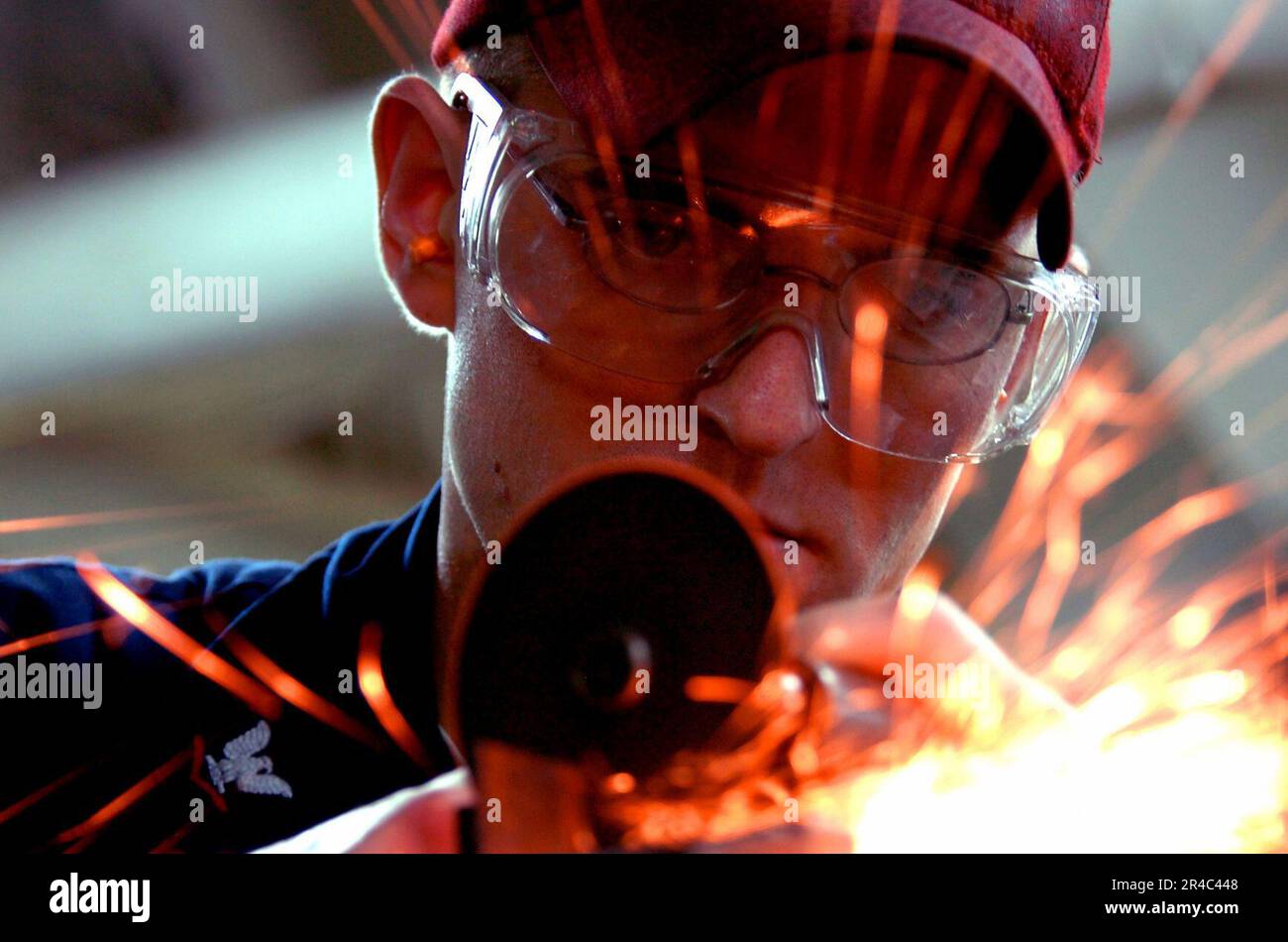 US Navy Hull Maintenance Technician 3rd Class works on a steel bracket ...