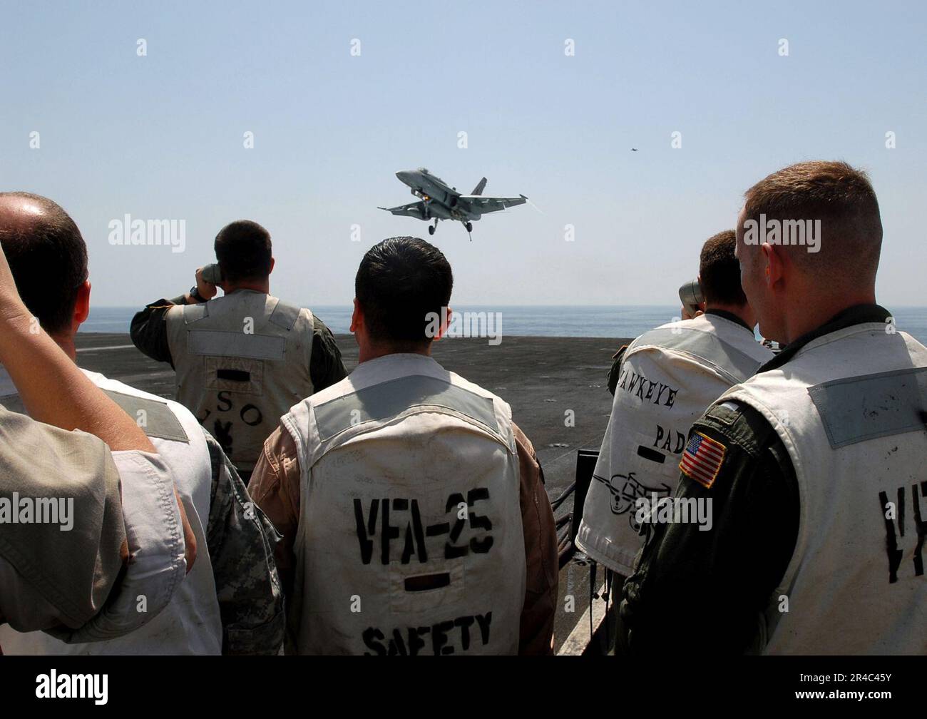 US Navy Landing signal officers (LSOs) observe an F-A-18C Hornet as it ...