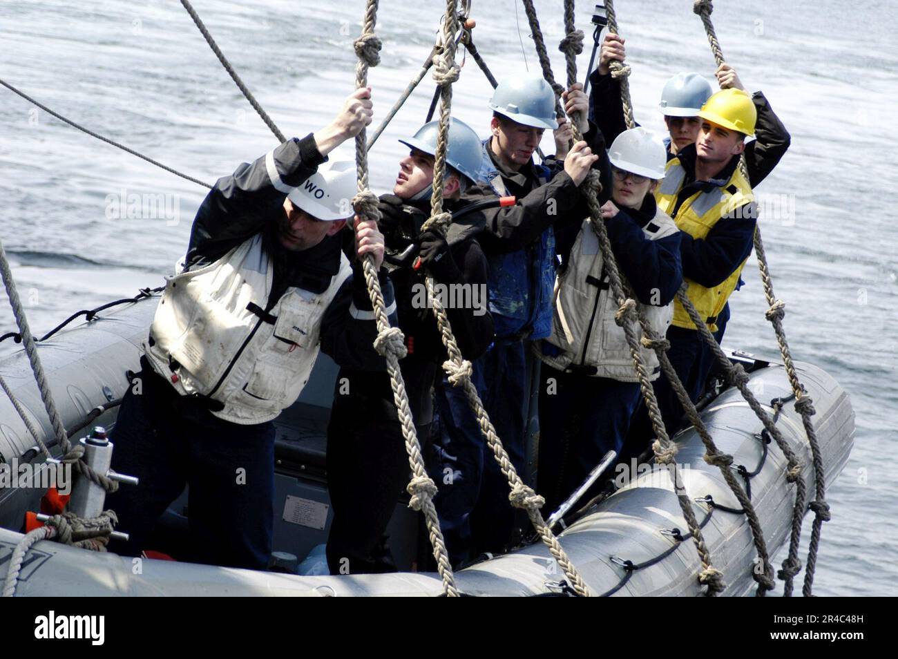 US Navy Sailors from deck department lower a rigid hull inflatable boat ...