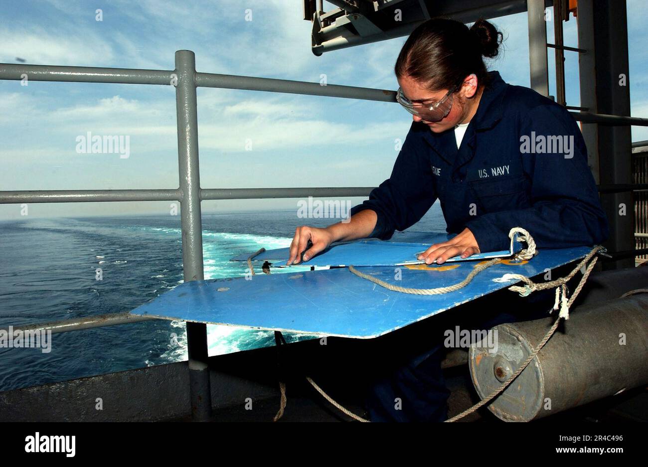 US Navy Seaman prepares mooring line rat guards in preparation for ...