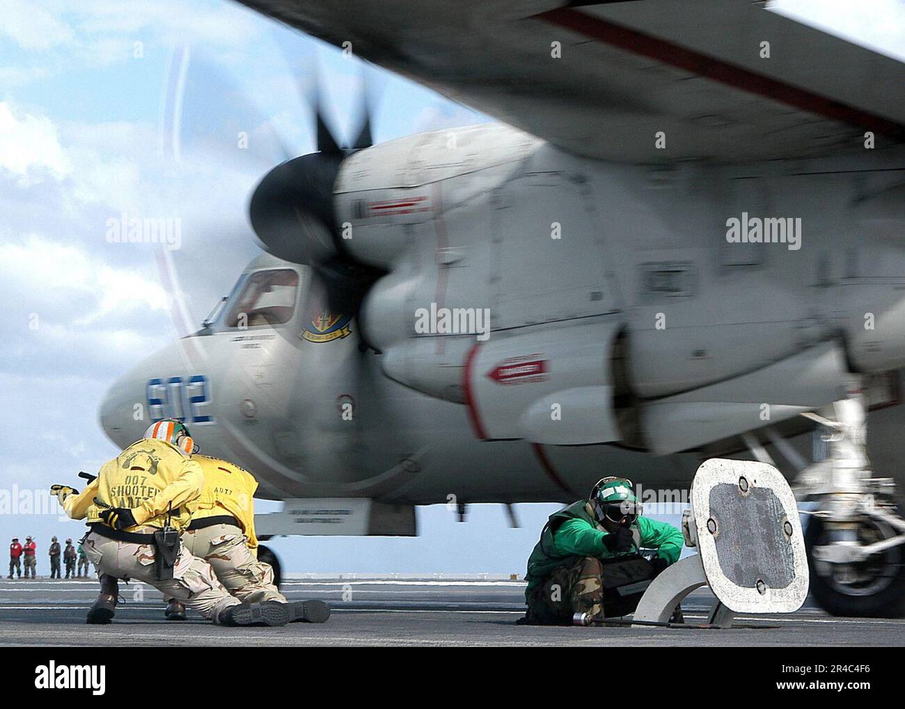 US Navy Flight Deck crew members signal for a safe launch of an E-2C ...