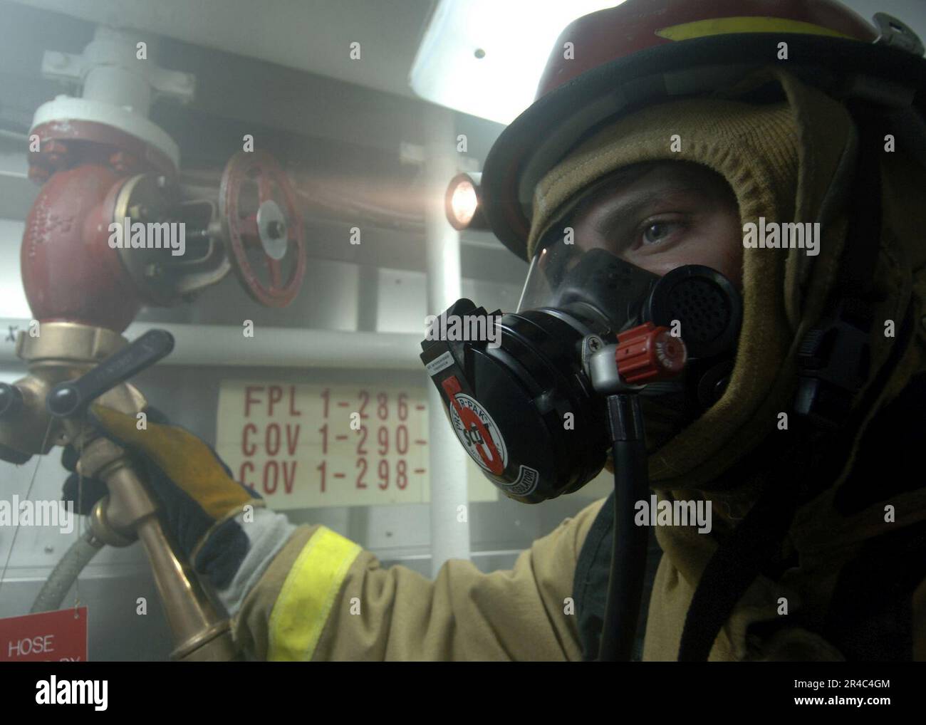 US Navy Seaman prepares to engage the plug valve of a fire hose during ...