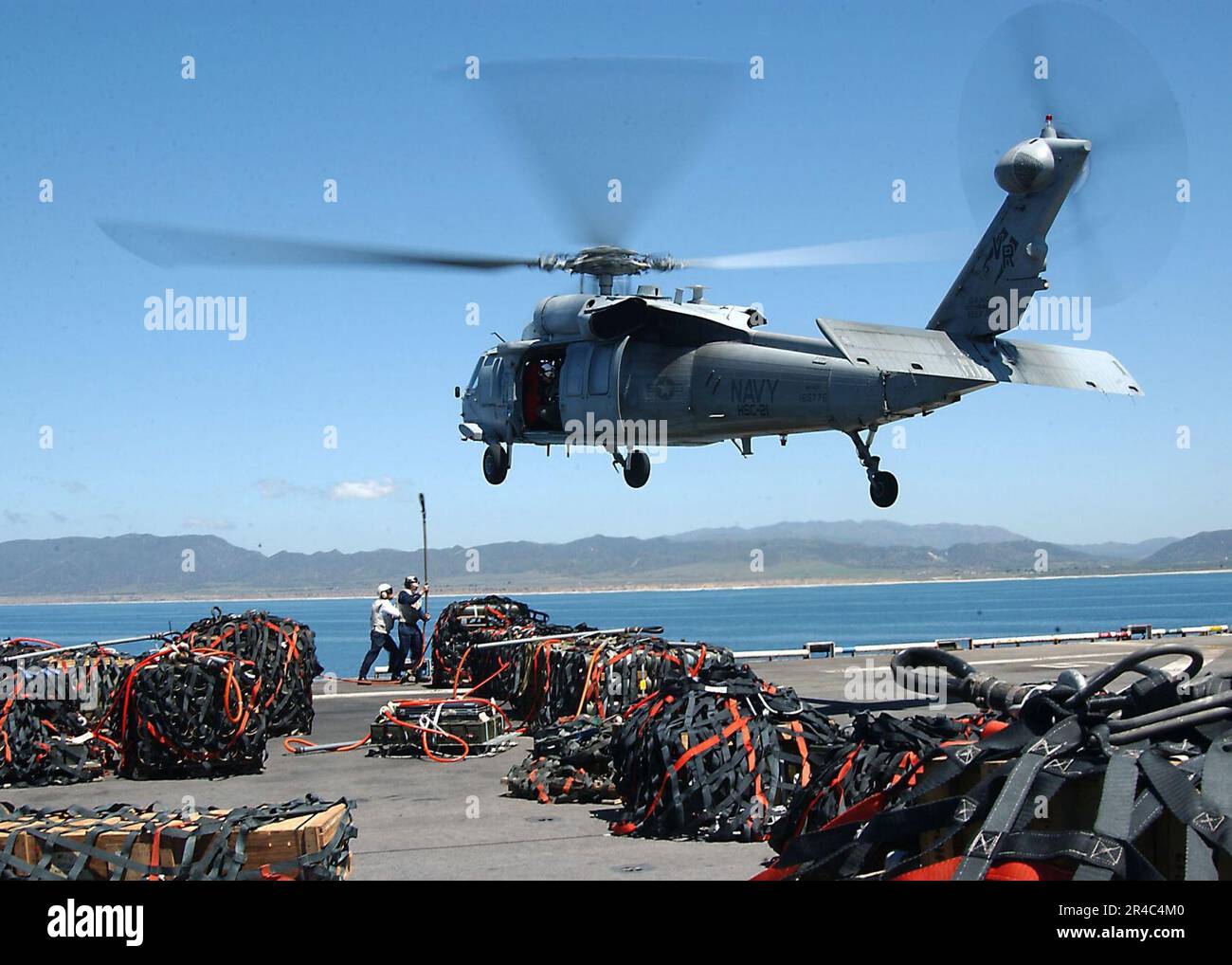 US Navy Two Sailors prepare to attach a cargo pendant to a MH-60S ...