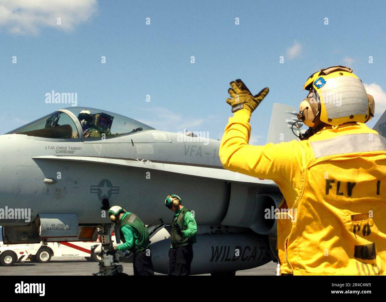 US Navy A Sailor signals to the pilot of an F-A-18C Hornet assigned to the Wildcats of Strike ...