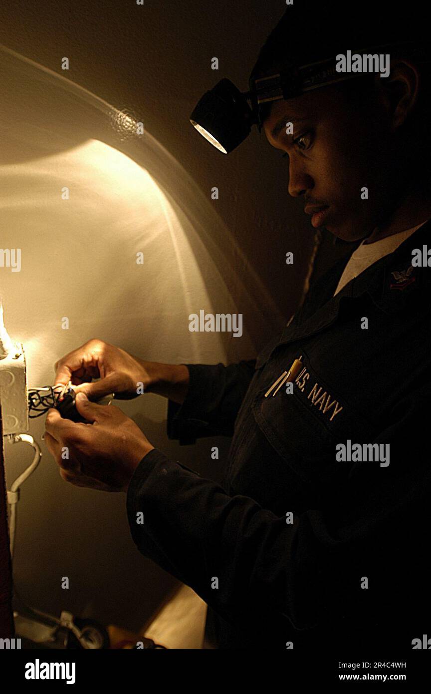 US Navy Electrician's Mate 2nd Class replaces a light switch aboard the ...