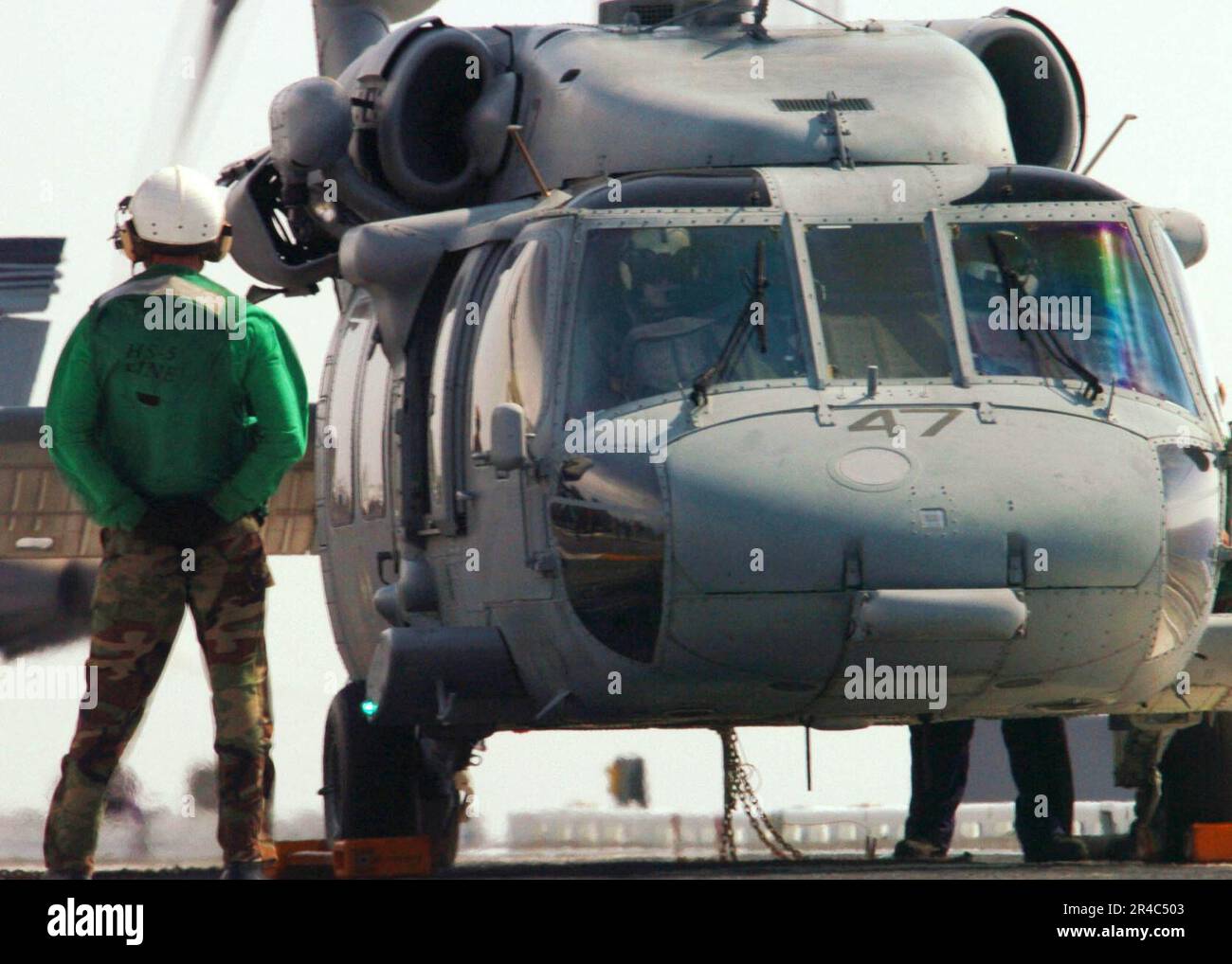 US Navy A Sailor stands in front of an MH-60S Seahawk helicopter ...