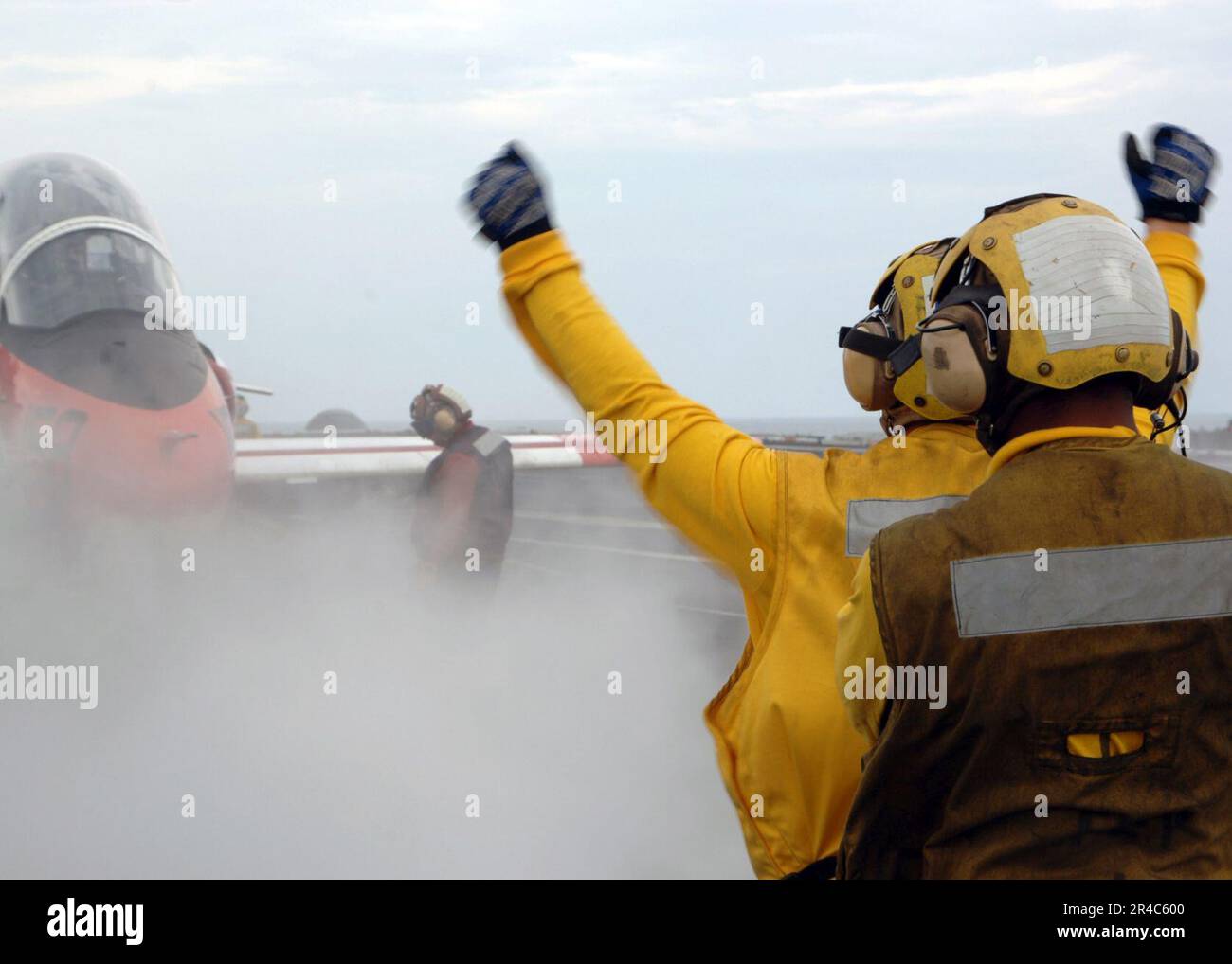 US Navy A flight deck plane director guides a T-45A Goshawk toward the ...