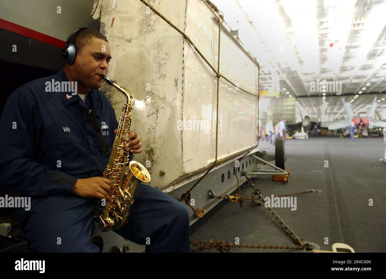 US Navy Quartermaster 3rd Class plays his saxophone in the hangar bay ...