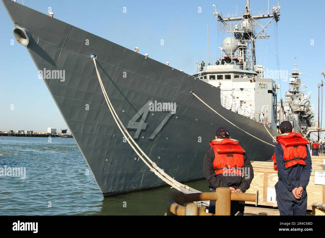 US Navy Sailors man the rail as line handlers wait to get the guided ...