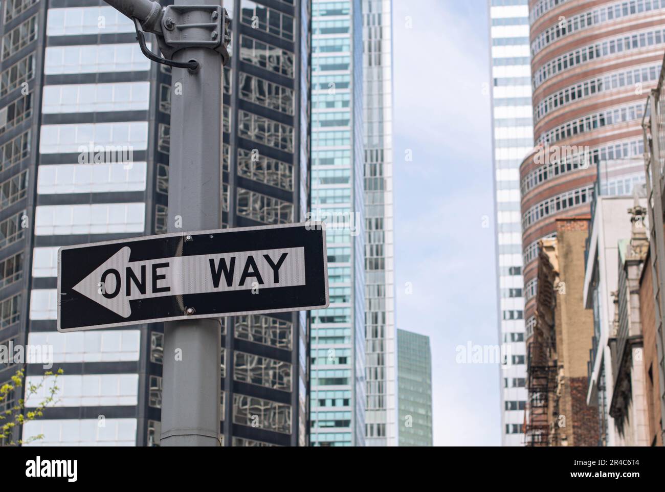 A black one-way street sign is affixed to a brick wall in an urban ...