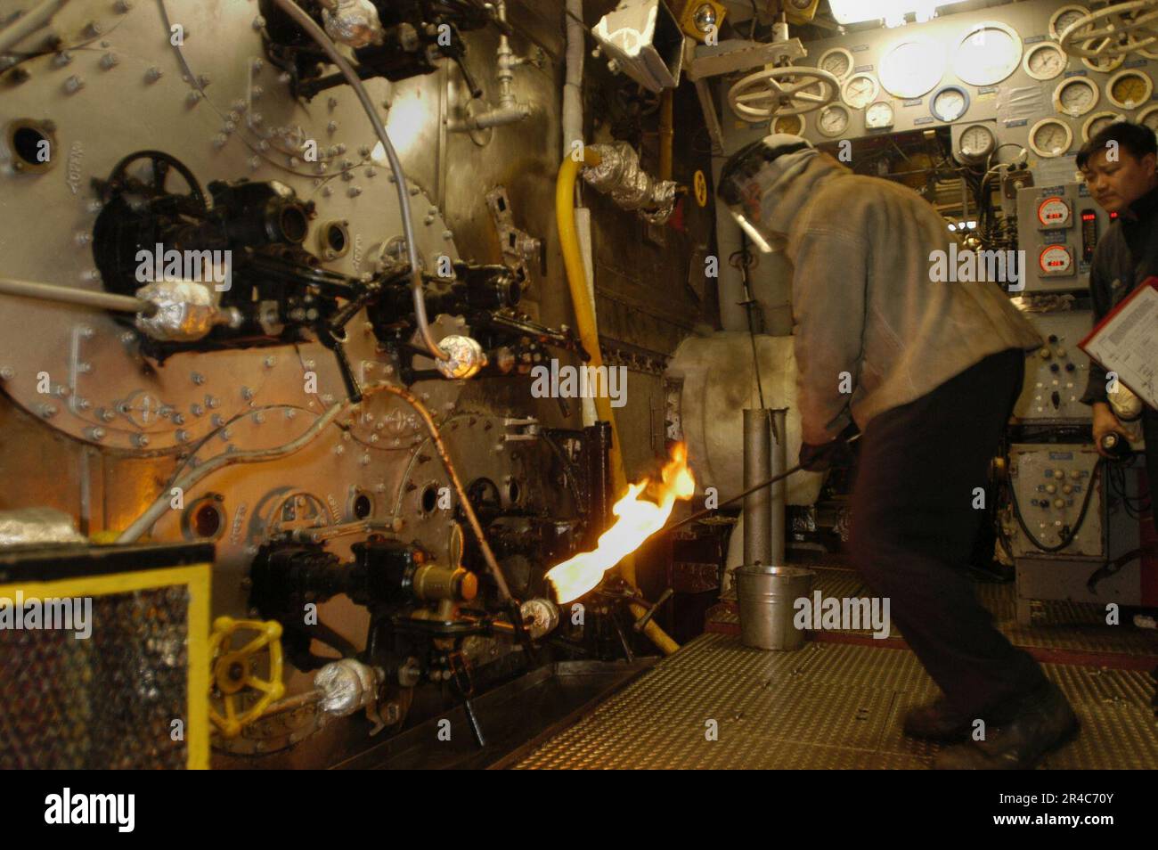 US Navy Machinist's Mate 3rd Class prepares to ignite a boiler during a ...