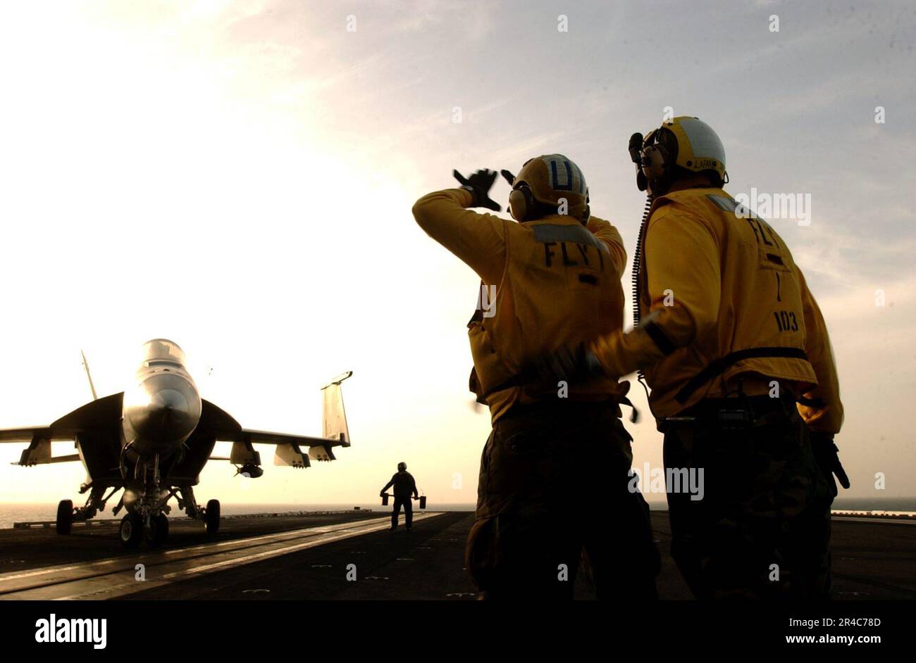 US Navy A plane director provides visual signals for an F-A-18E Super ...