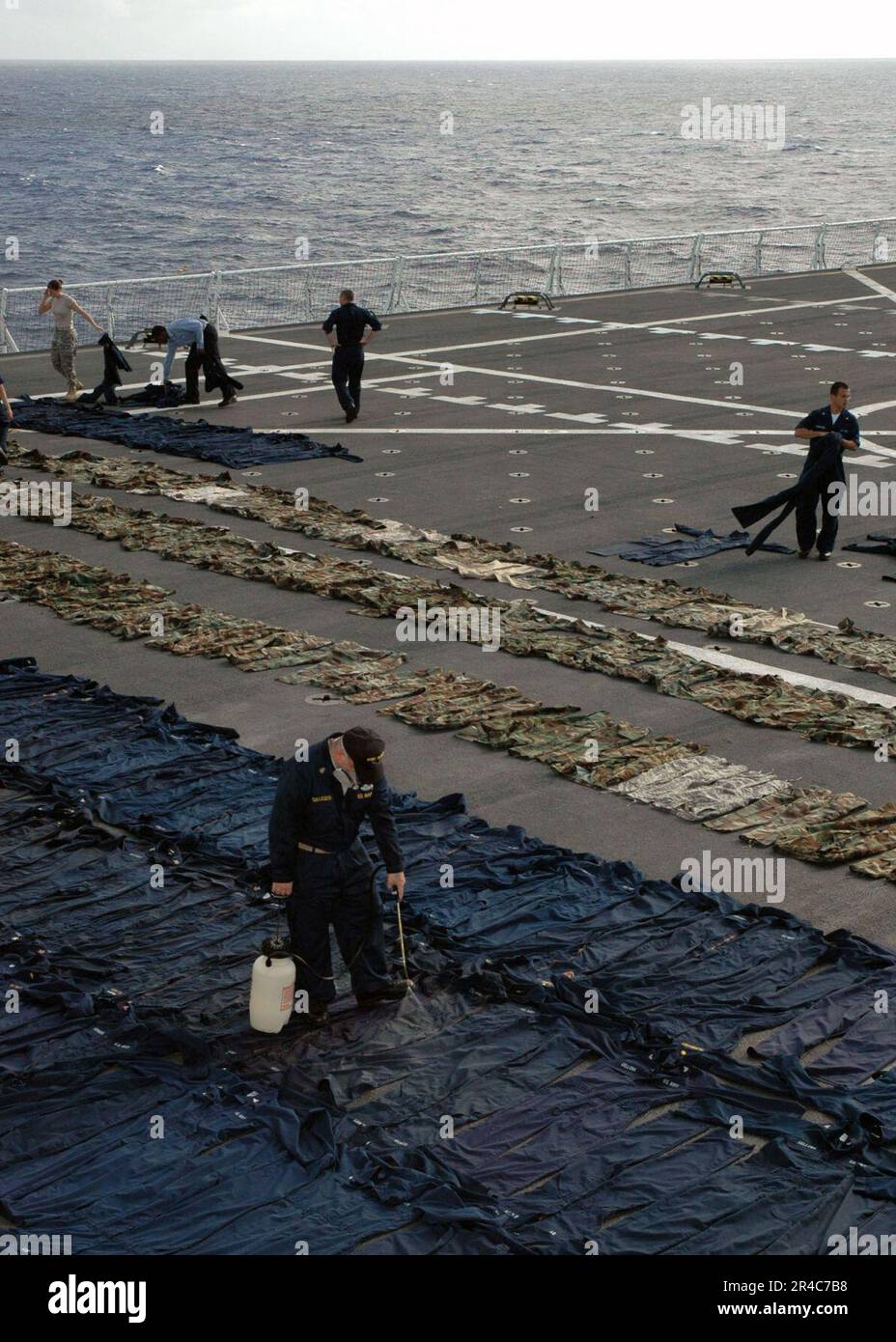US Navy Crew members prepare uniforms to be sprayed with Permethrin on ...