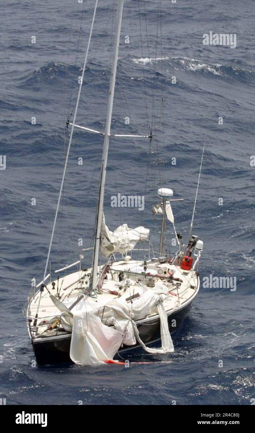 US Navy A sailboat rides low at the bow with torn sails on the main ...