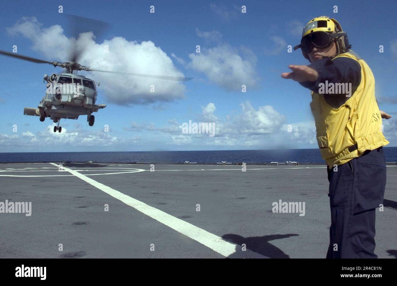 US Navy Quartermaster 3rd Class directs an SH-60B helicopter assigned ...