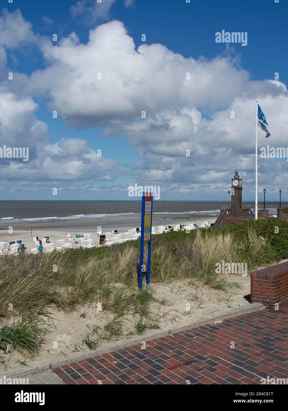 A sandy shore with multiple beach chairs and a clock tower in ...