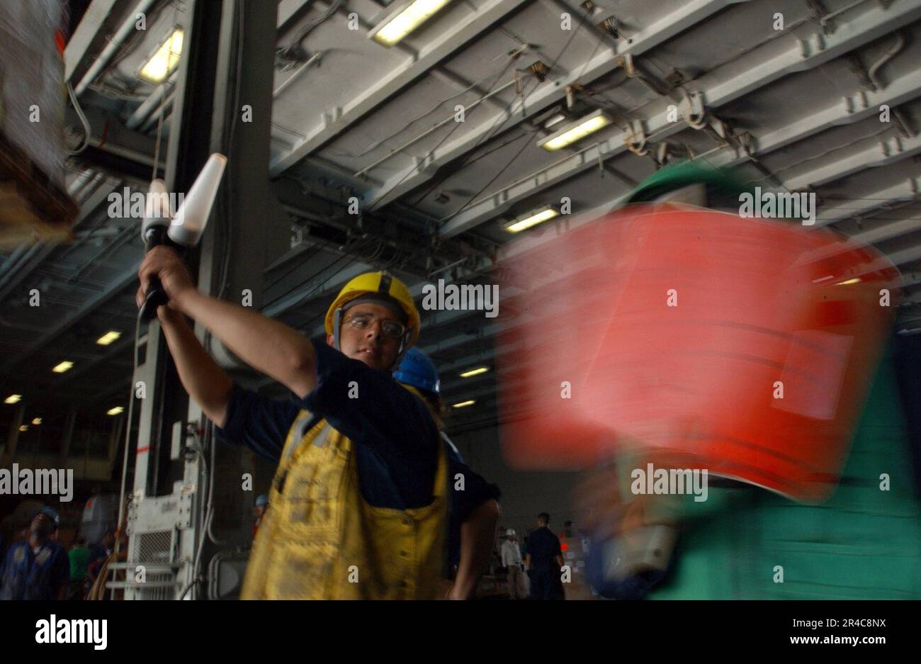 US Navy Boatswain's Mate 3rd Class gives the stop signal for a cargo ...